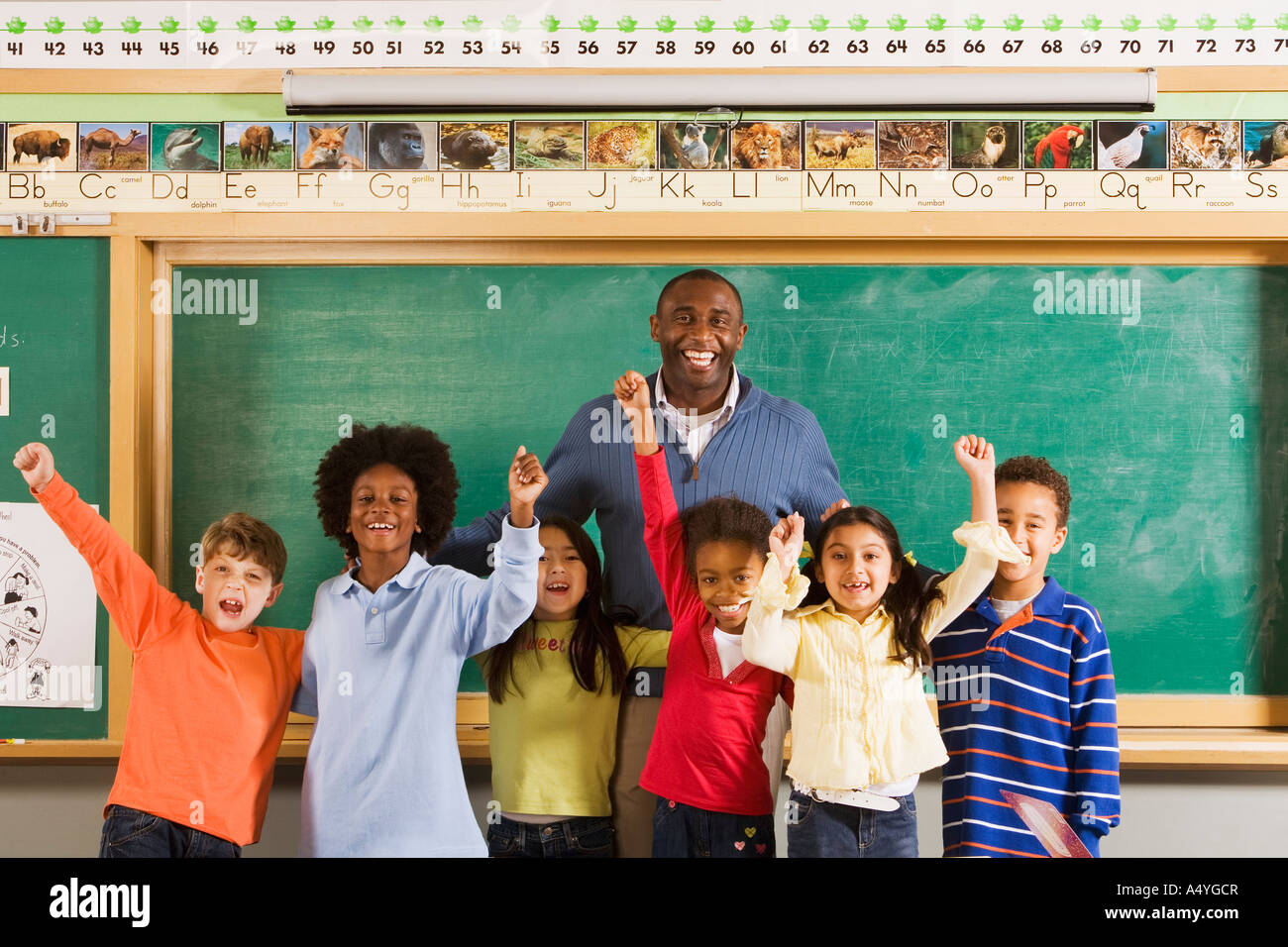 Male teacher and students cheering in classroom Stock Photo - Alamy