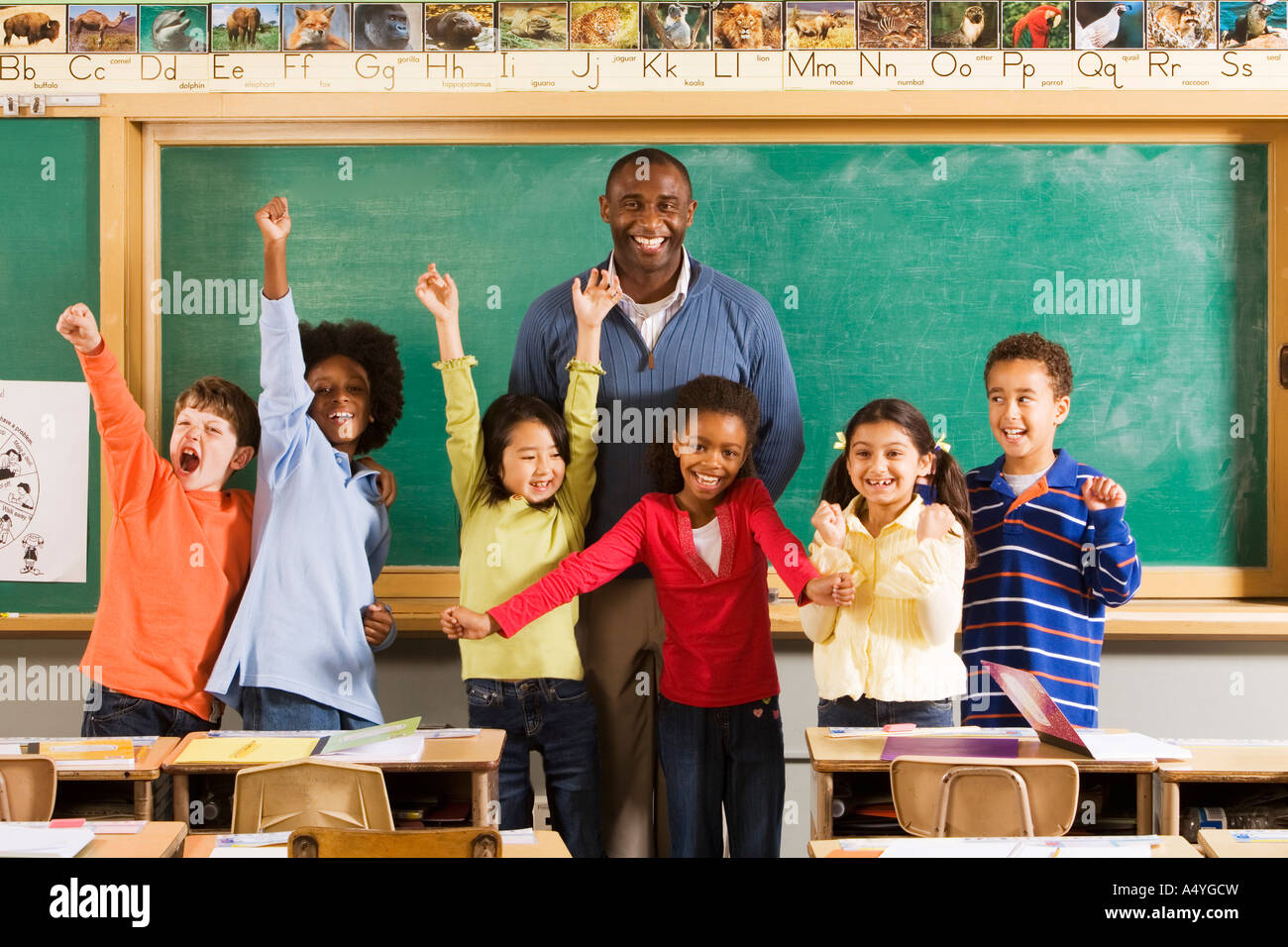 Male teacher and students cheering in classroom Stock Photo - Alamy