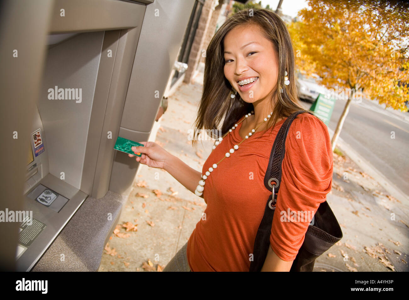 Woman smiling and using ATM Stock Photo - Alamy