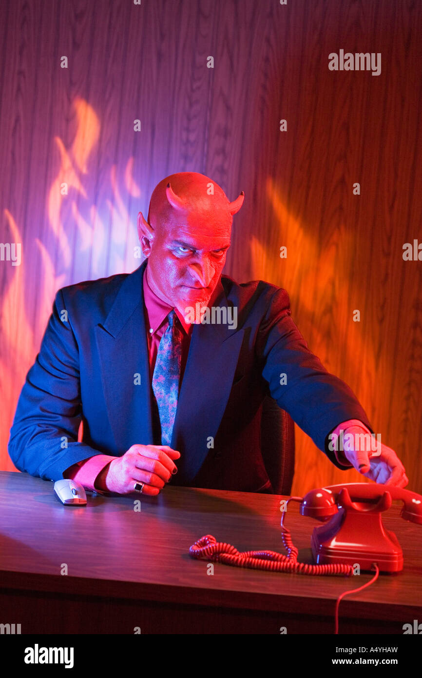 Businessman dressed as devil at desk Stock Photo - Alamy