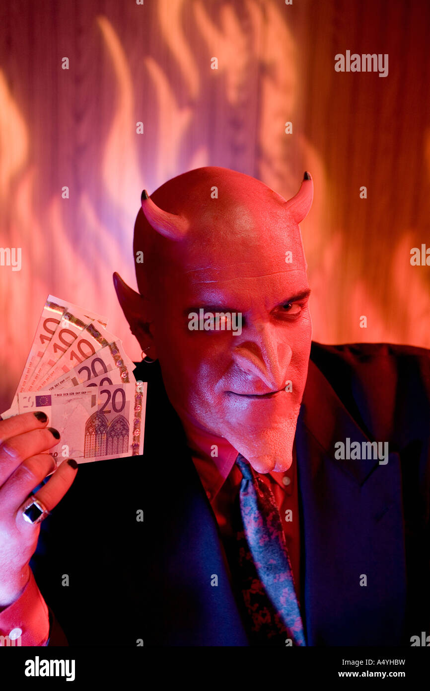 Businessman dressed as devil holding money Stock Photo - Alamy