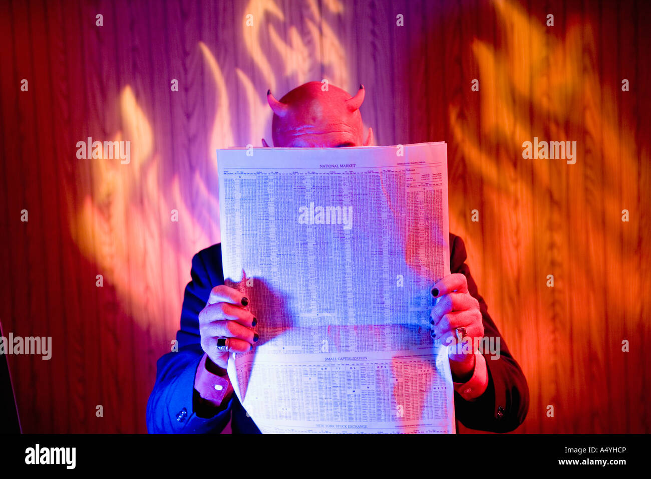 Businessman dressed as devil reading newspaper Stock Photo - Alamy
