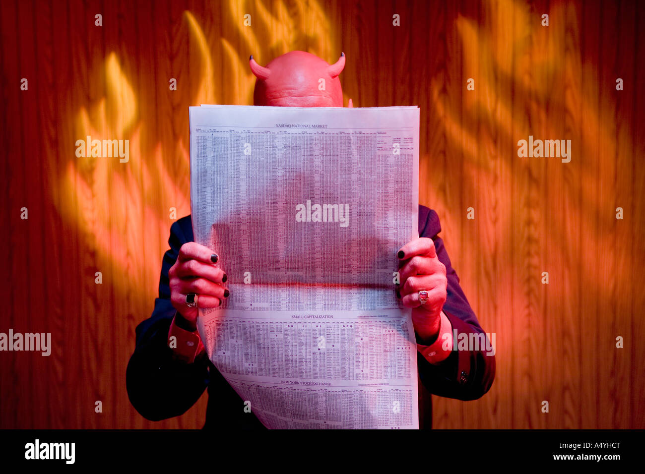 Businessman dressed as devil reading newspaper Stock Photo - Alamy
