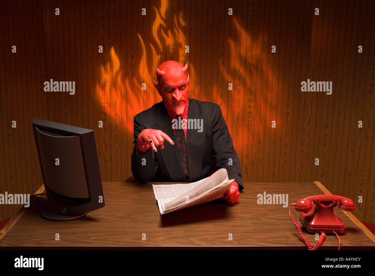 Businessman dressed as devil reading newspaper Stock Photo - Alamy