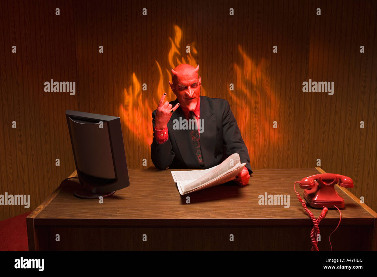 Businessman dressed as devil reading newspaper Stock Photo - Alamy