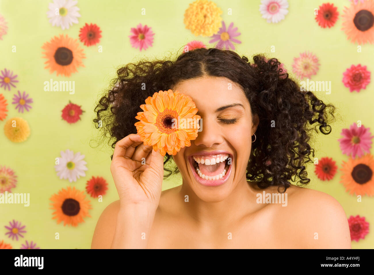 Woman laughing and holding flower over eye Stock Photo - Alamy