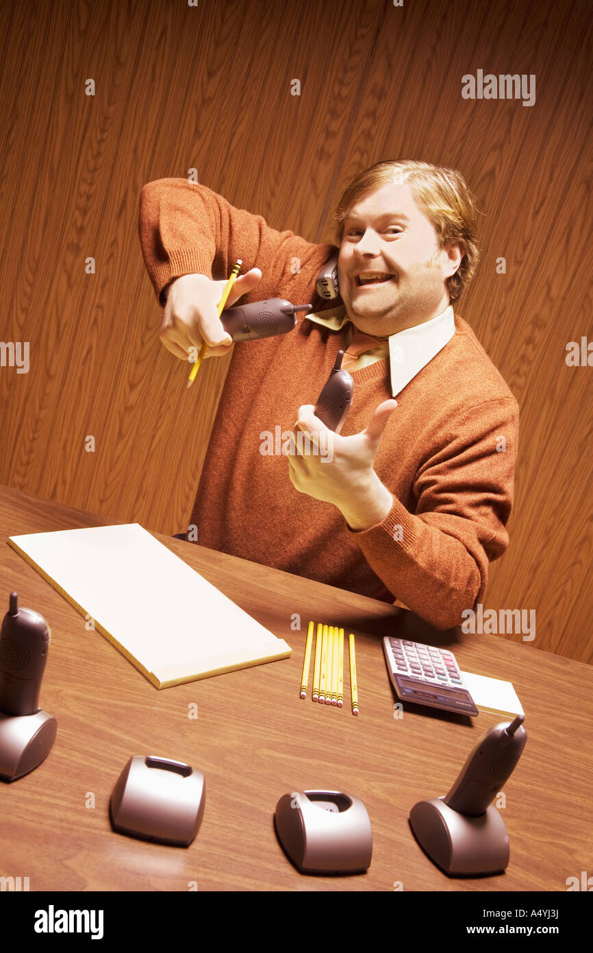 Businessman at desk using multiple telephones Stock Photo - Alamy