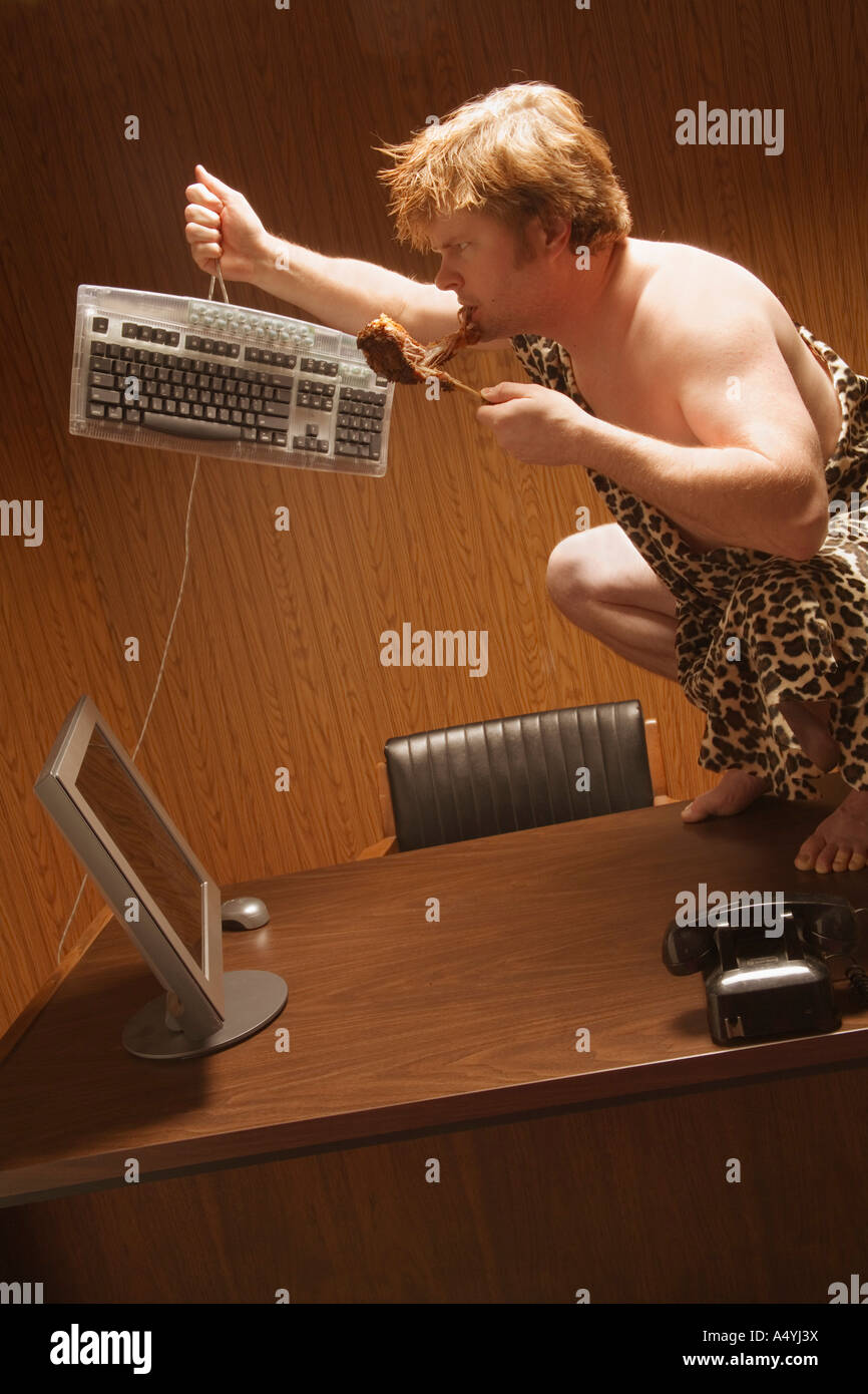 Businessman dressed as caveman crouching on desk Stock Photo - Alamy