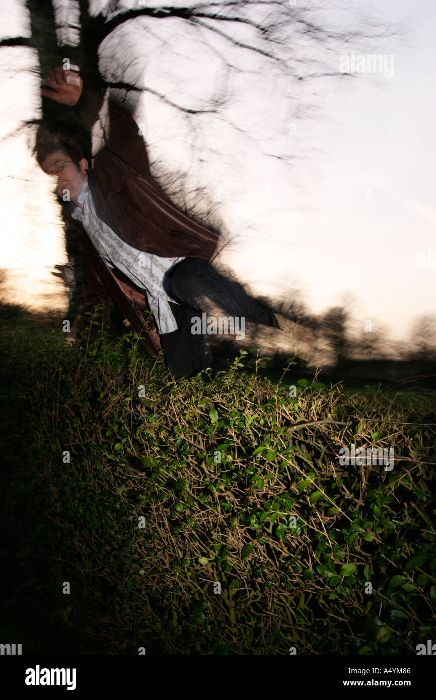 Man jumping over park hedge with leafless branches and church steeple ...