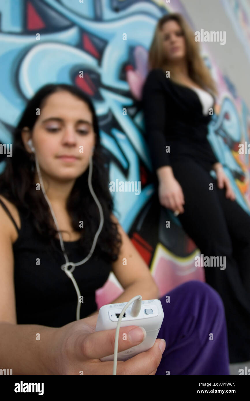 Two girls chilling out beside graffiti-covered wall Stock Photo - Alamy