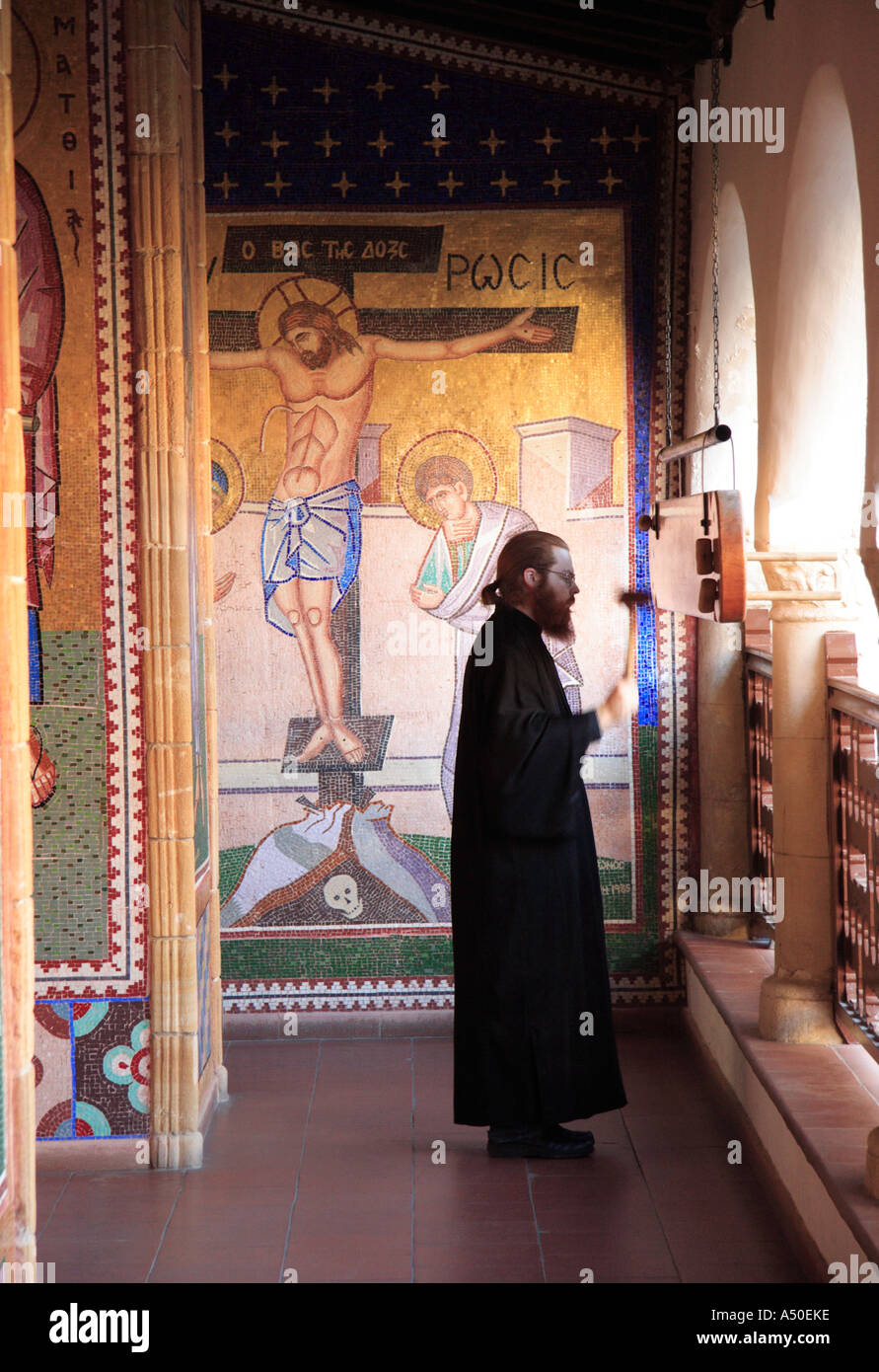 A Greek Orthodox monk calls fellow monks to prayer by banging wooden ...