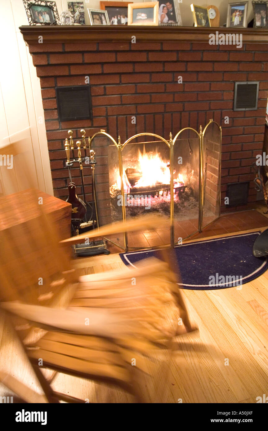Rocking chair with movement next to a brick fireplace with lit fire ...