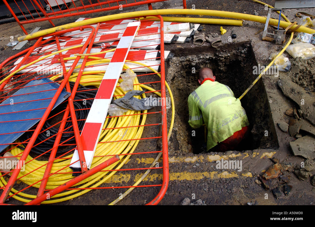 Workman laying gas pipes in a hole in the road Stock Photo - Alamy