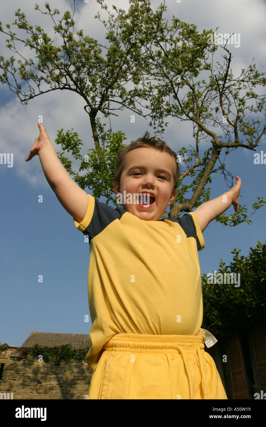 Small boy pretending to be a tree with apple tree in background Stock ...