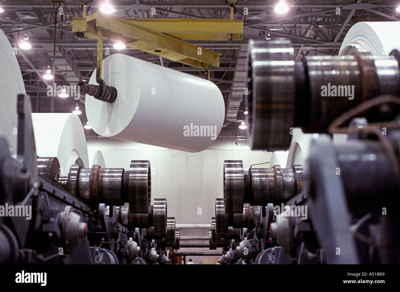 Interior of a paper mill showing a massive overhead crane handling a 50 ...