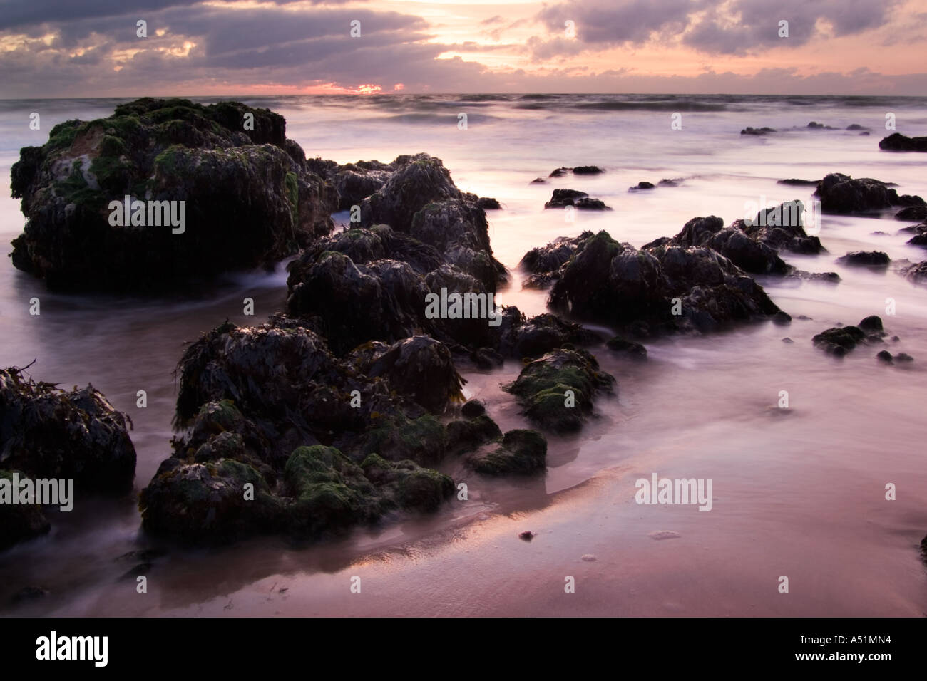 Sunset on Compton Beach with rocks and sand in foreground Isle of Wight ...
