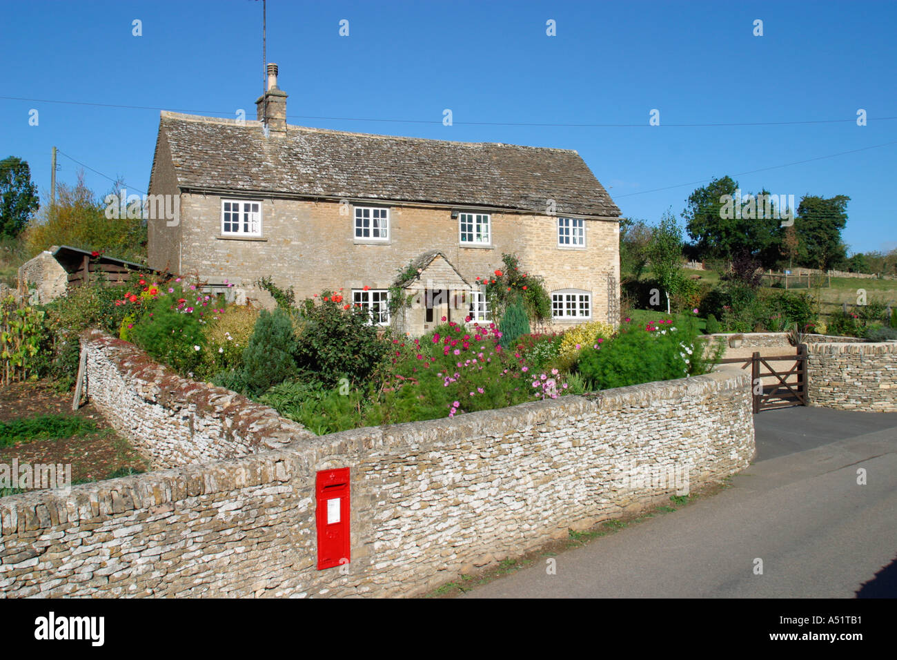 Vibrant red post boxand acotswold cottage, Coln Rogers, Cotswolds ...