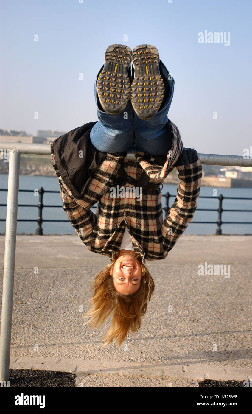 woman swinging upside down inverted on rail having fun Stock Photo - Alamy