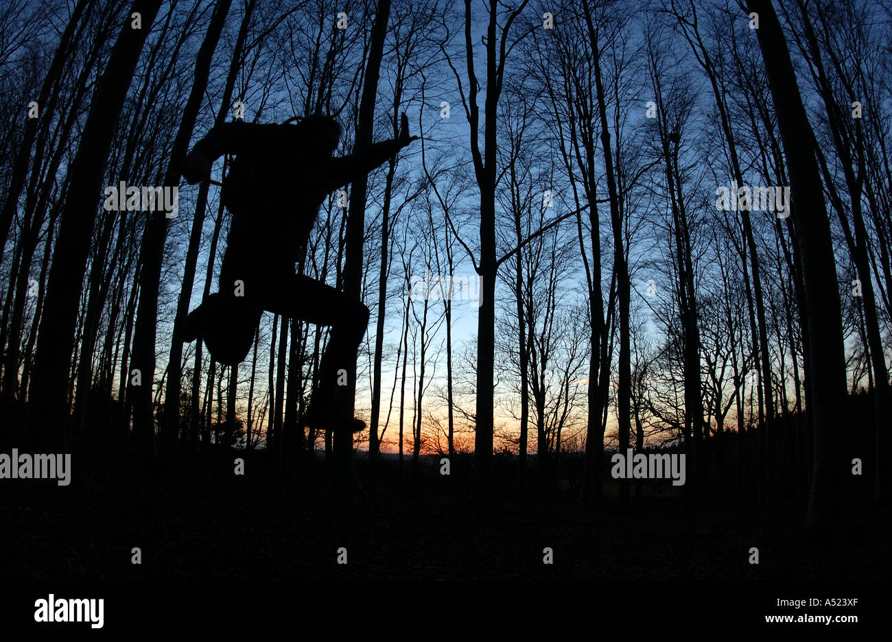 abstract of man silhouetted jumping through trees at sunset having fun ...