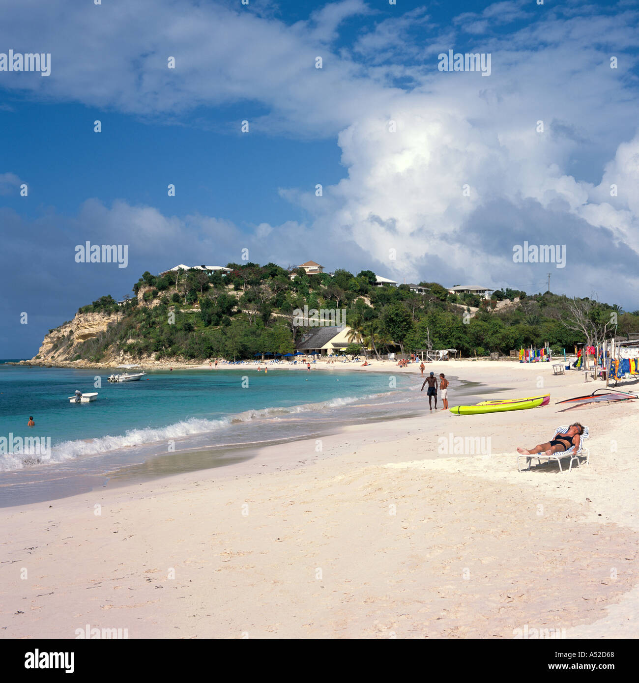 Woman tourist sunbathing on beach with distant people and kayaks at ...