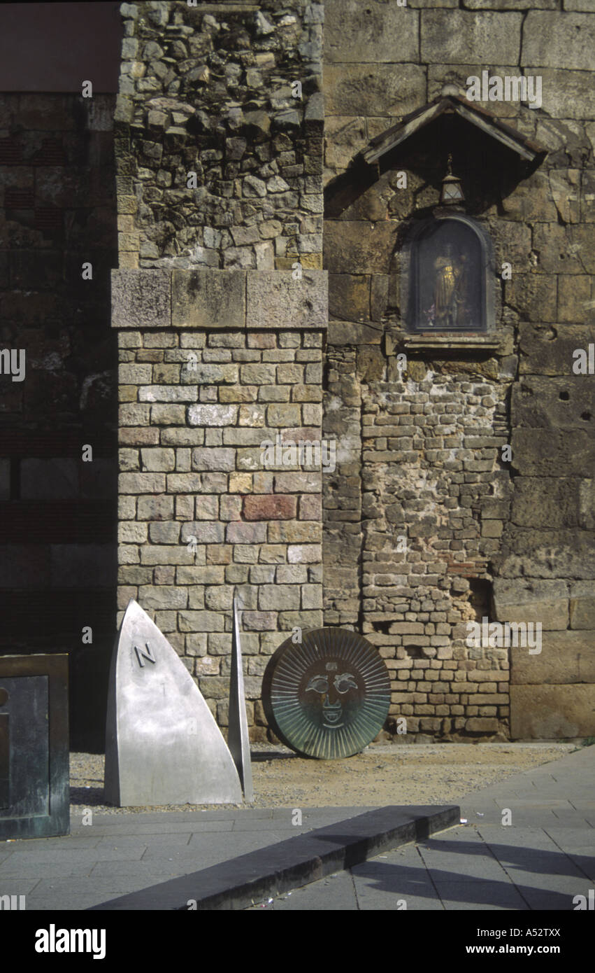 Iron letters of the Barcino sculpture and sun lit stone wall and Saint ...