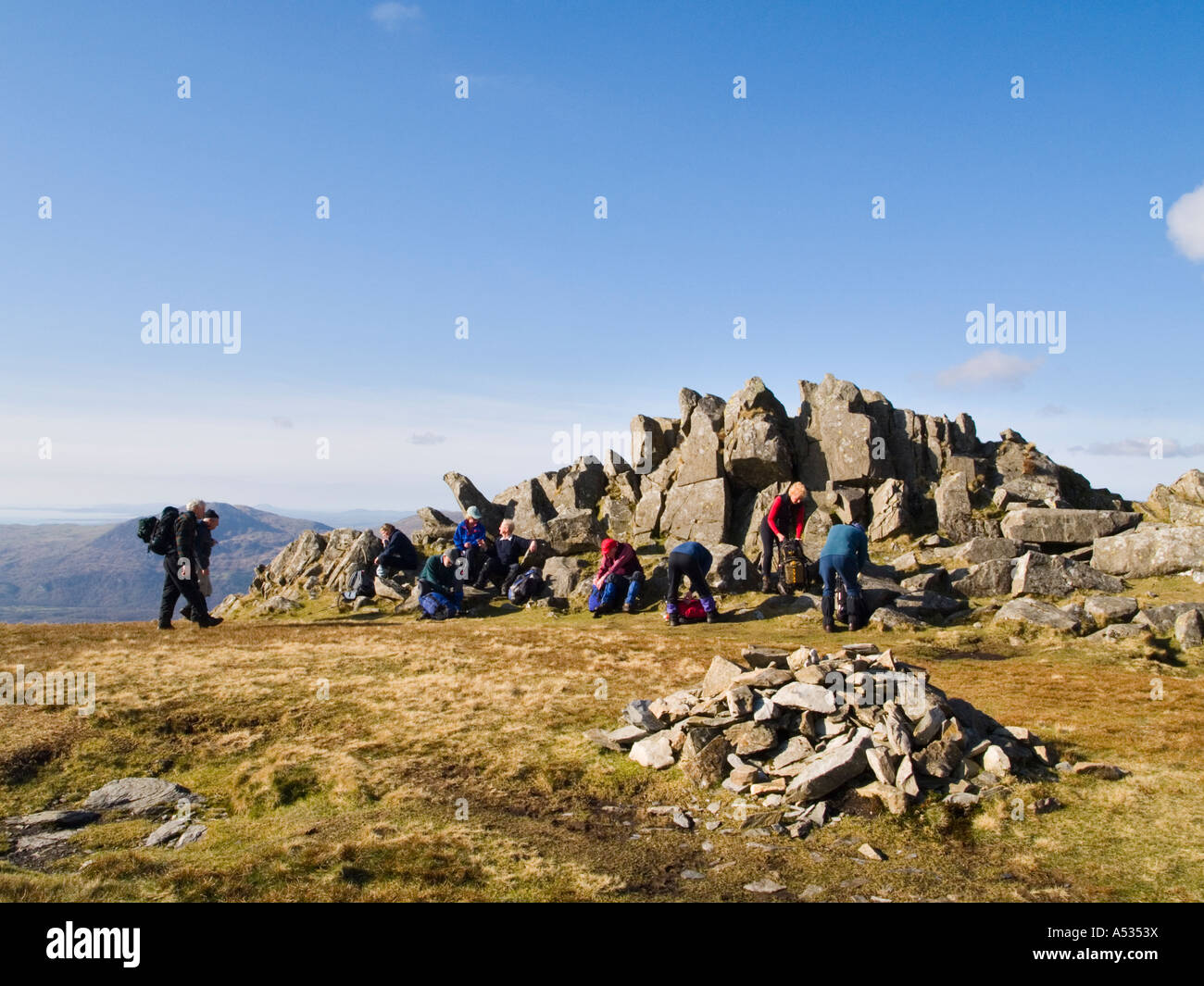 Ramblers group resting by rock on path up Cnicht mountain in Snowdonia ...
