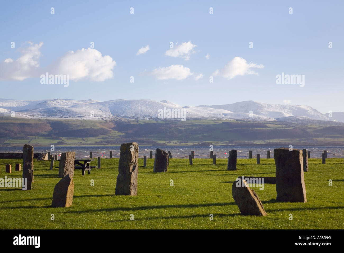 Stone circle on seafront with snow covered mountains of Snowdonia ...