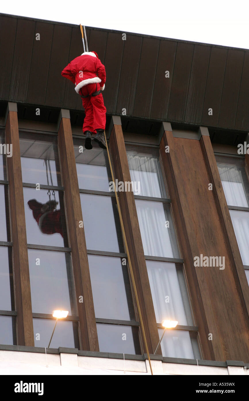 A santa is climbing down a rope on a big house Stock Photo - Alamy
