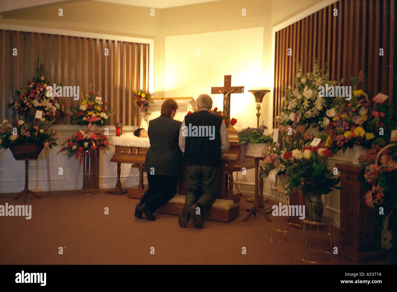 Couple kneeling before open coffin at Catholic wake. Brooklyn Center ...