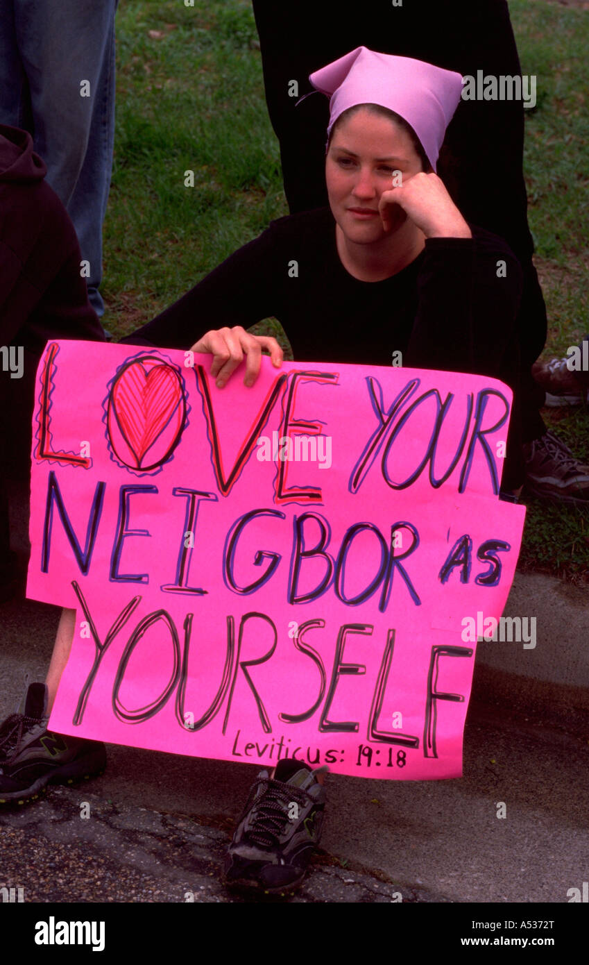 Woman holding a sign saying love your neighbor as yourself Leviticus 19 ...
