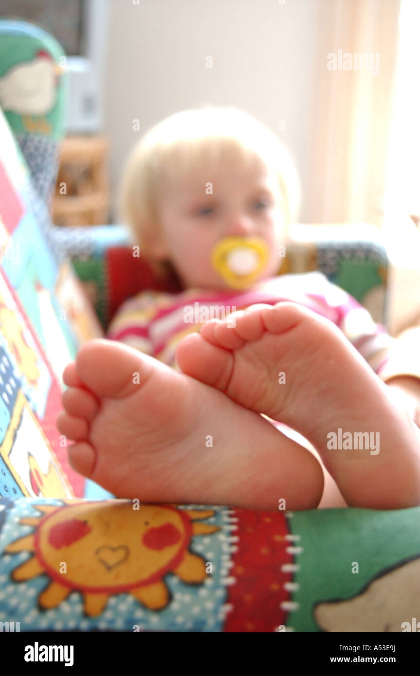 British toddler child laying on sofa with dummy with bare feet UK Stock ...