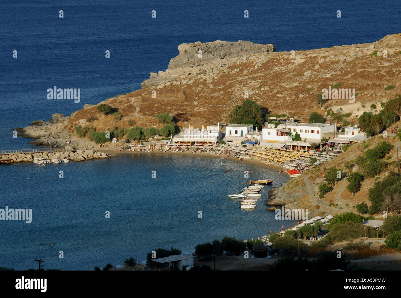 Early evening sun shines on a small beach at Lindos on the Greek island ...