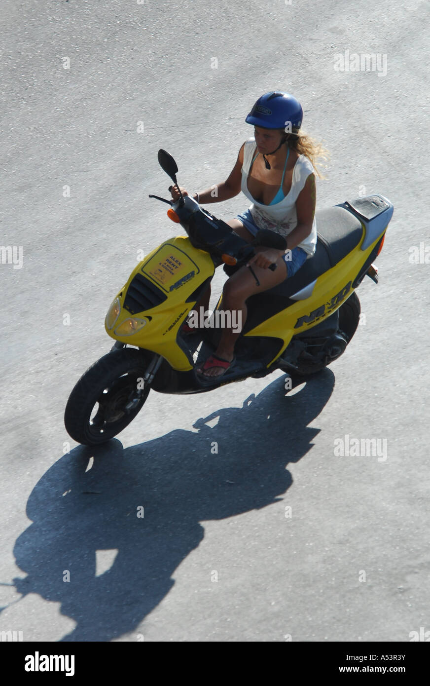 A young woman riding a scooter in Rhodes Town, Rhodes island Greece ...
