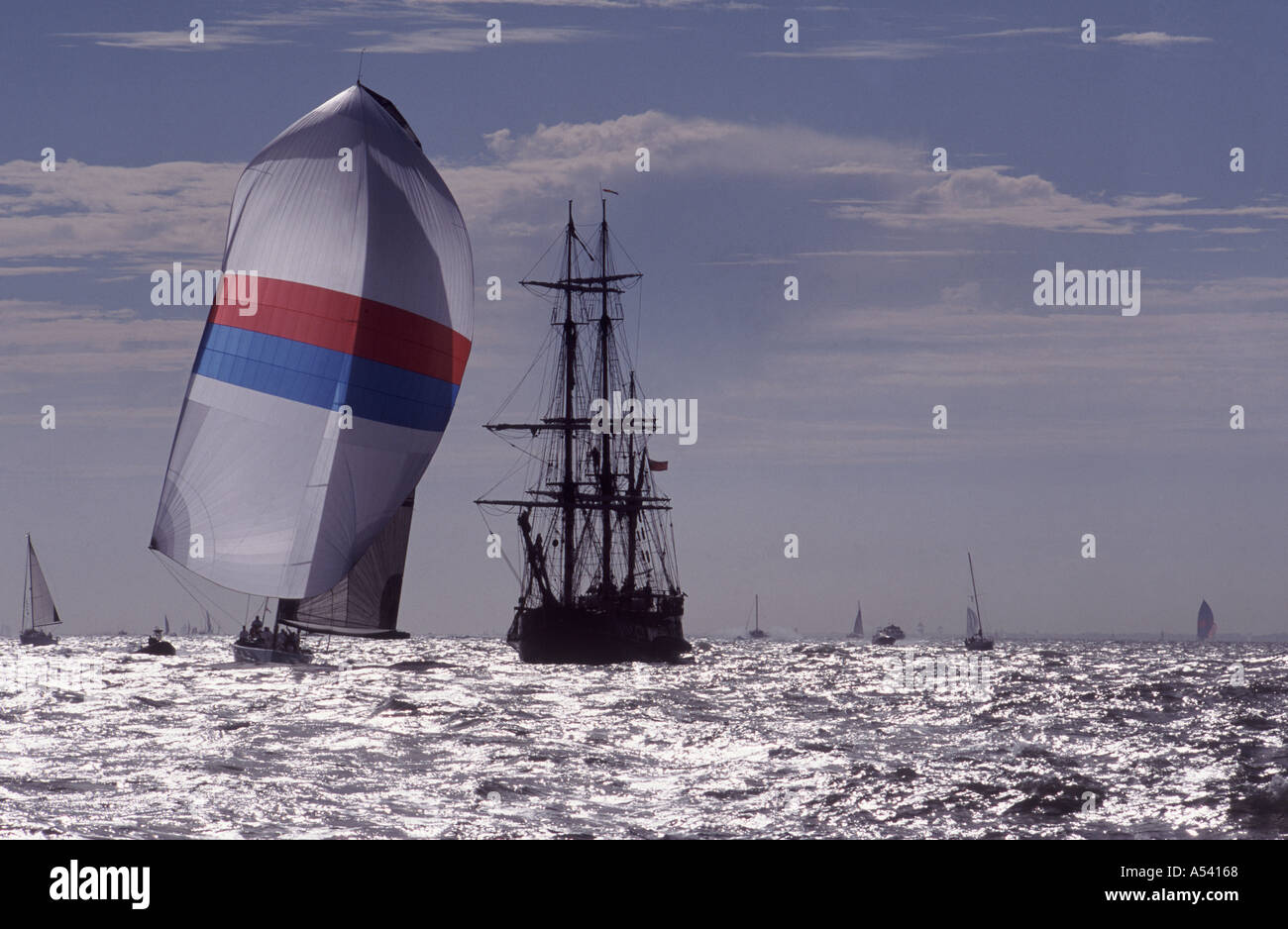 A yacht racing under spinnaker past a replica of square rigger, in the ...