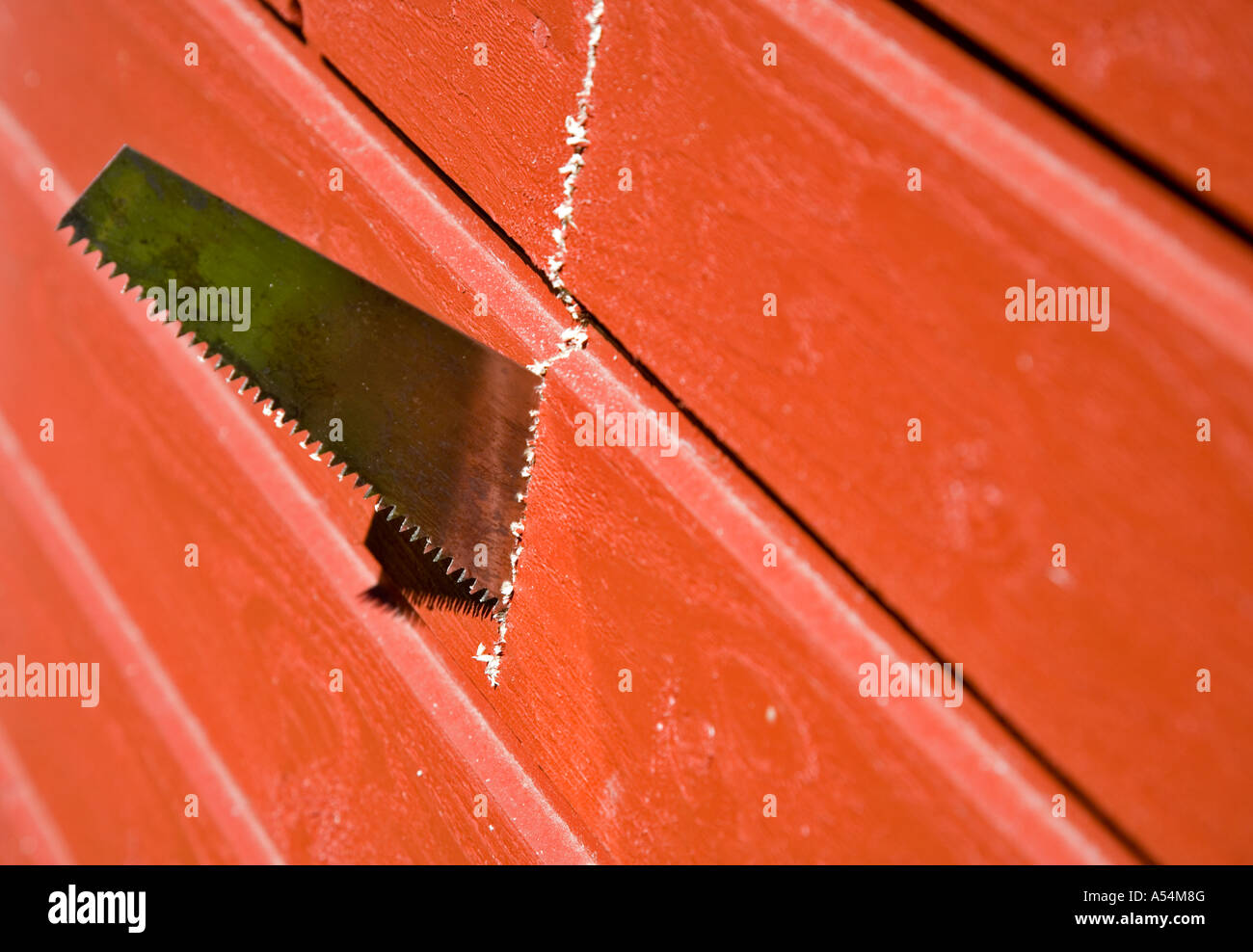 Sawing through a red plank wall using hand saw Stock Photo - Alamy
