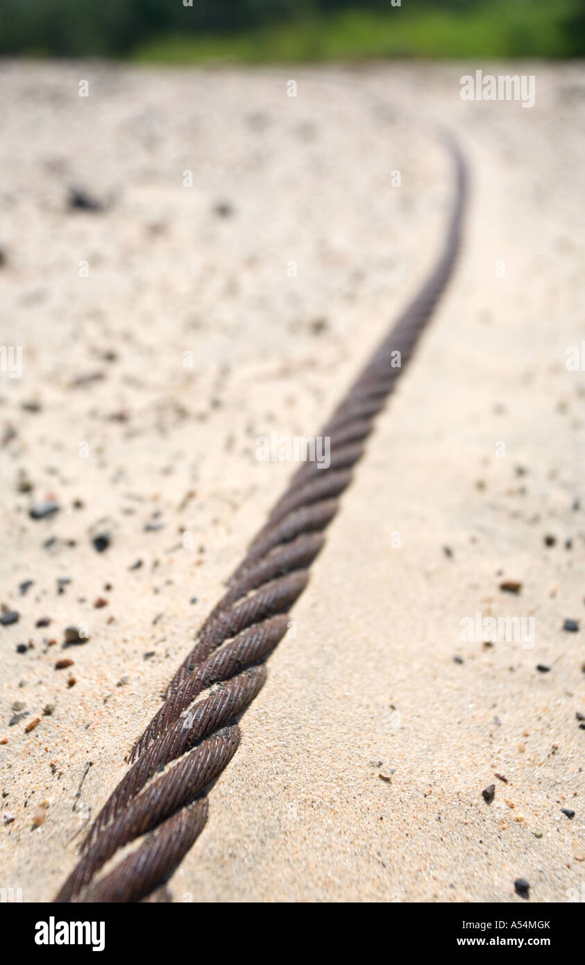 Rusty steel wire rope lying half buried to sand Stock Photo - Alamy