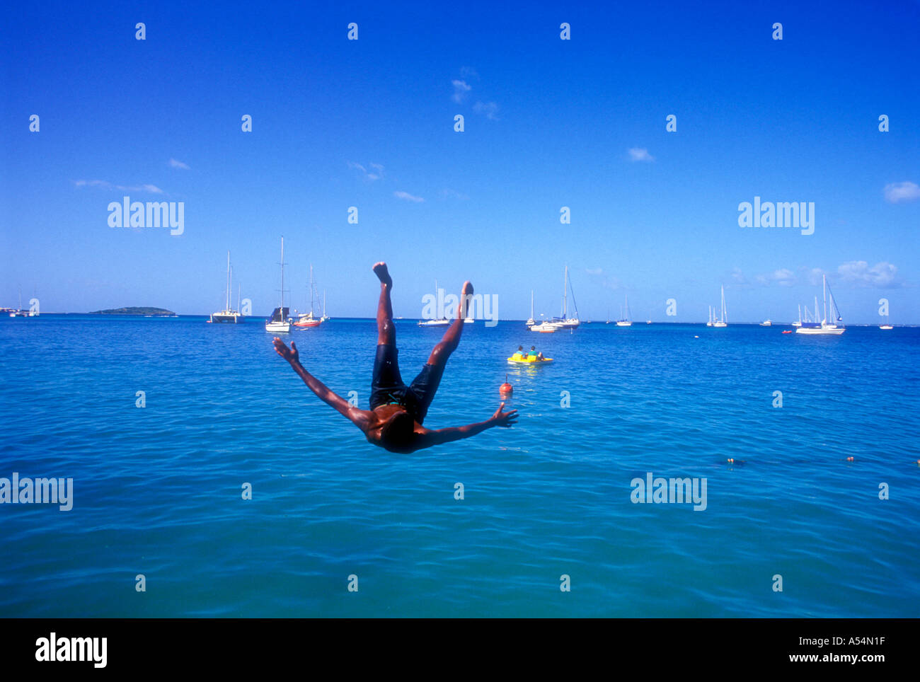 Boy jumping off dock into the ocean on the island of St Martin French ...