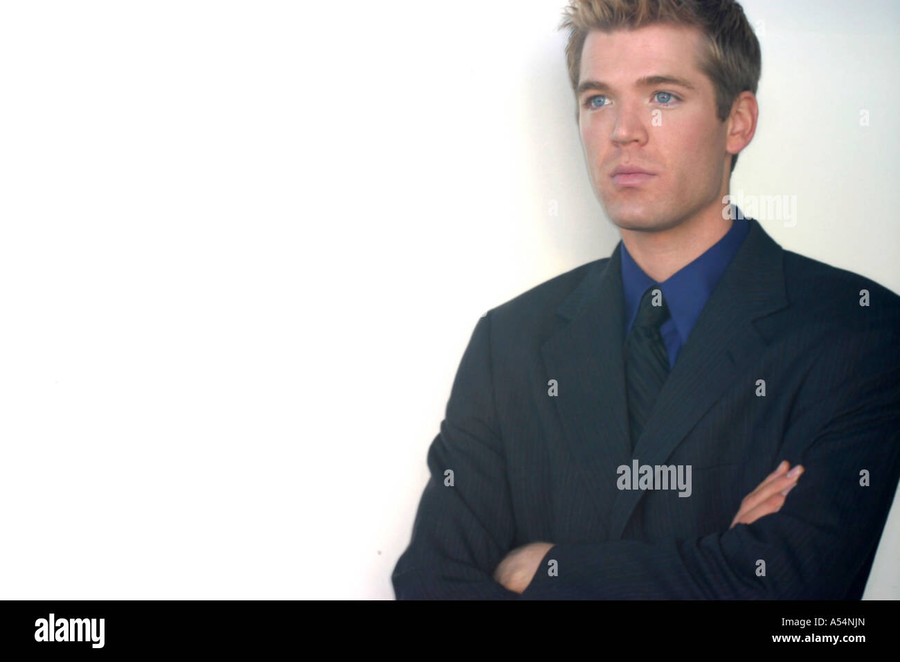 Blond hair blue eye businessman is folding his arms and has focused ...