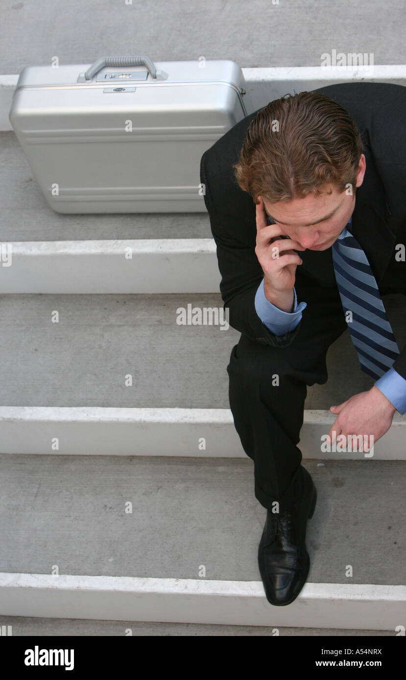 Business man in dark blue suit is sitting down talking on his cellphone ...