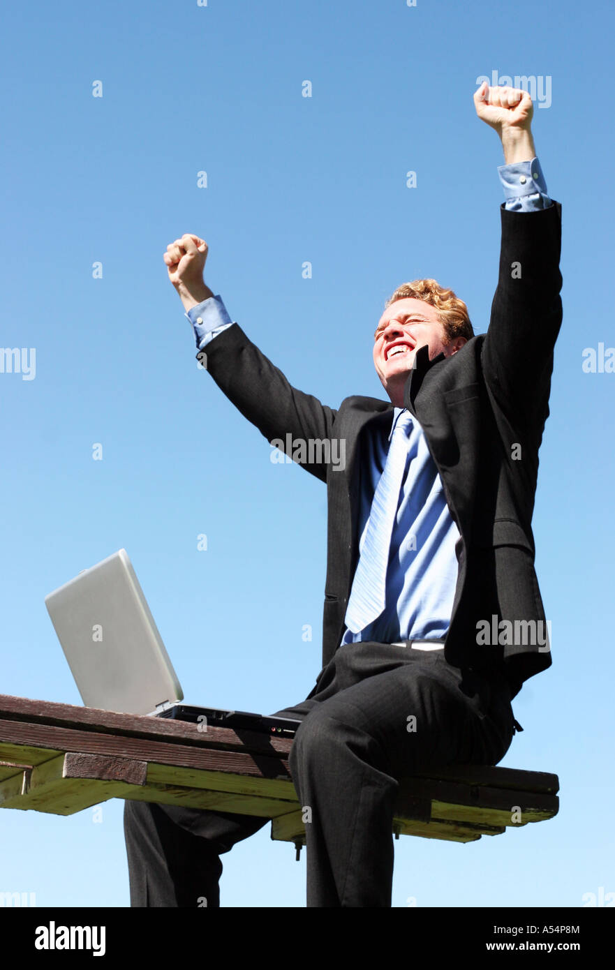 Businessman in black suit and blue shirt and tie is lifting his arms up ...