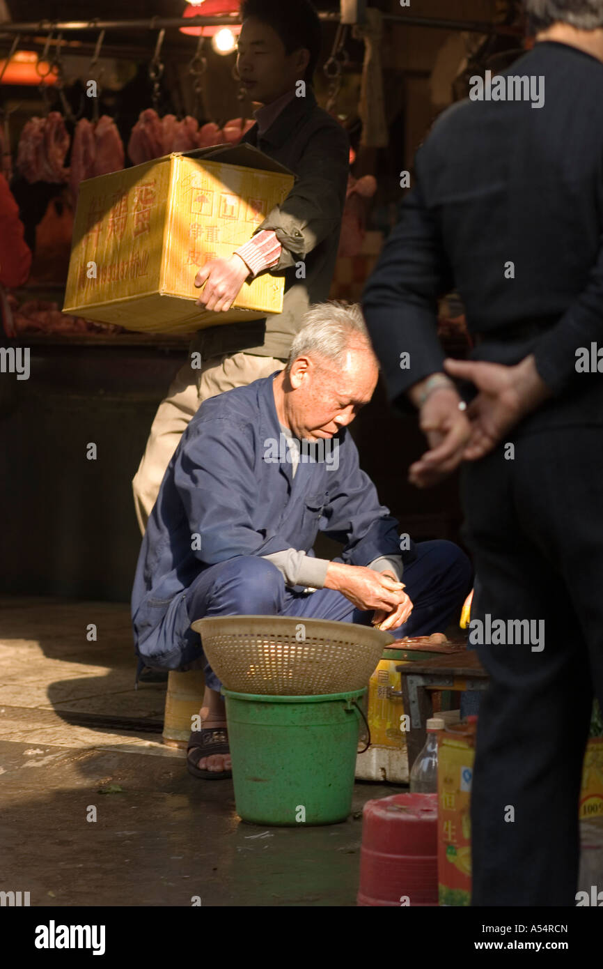Seated man in a meat market in Guangzhou China Stock Photo - Alamy