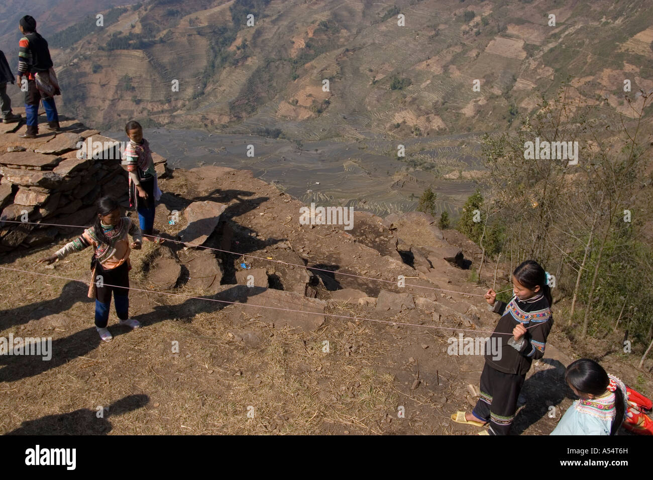 Children playing rope game and veiw ofand rice terraces Yuanyang China ...