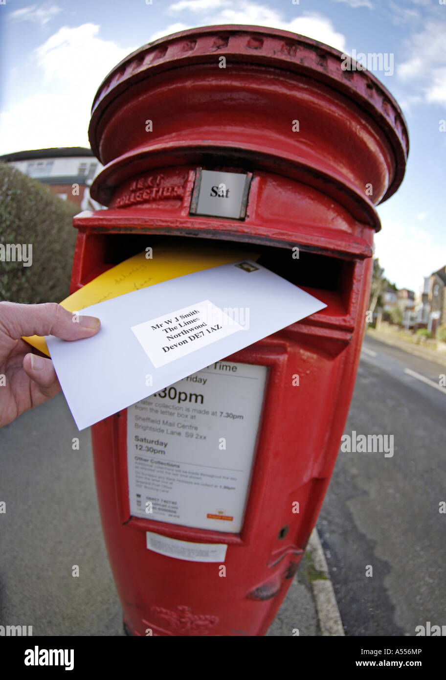 Posting letters in red pillar box England Stock Photo - Alamy