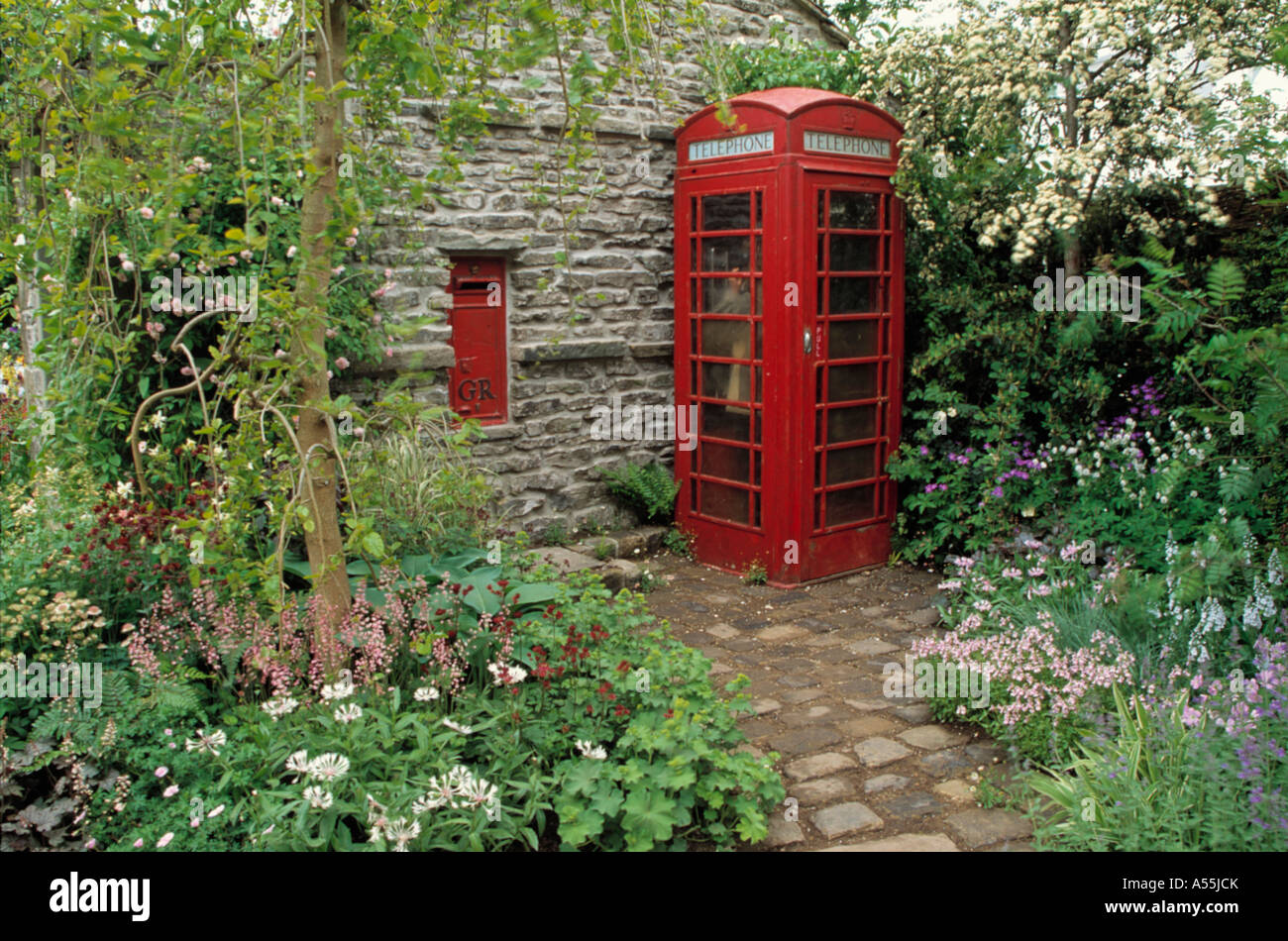 Red English telephone box against stone wall with red letterbox in ...