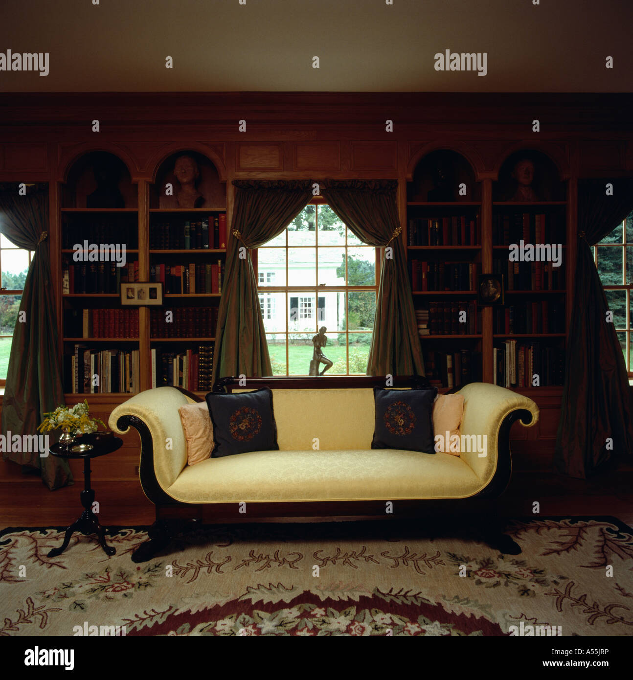 Cream Regency-style sofa in front of window with shelves on either side ...