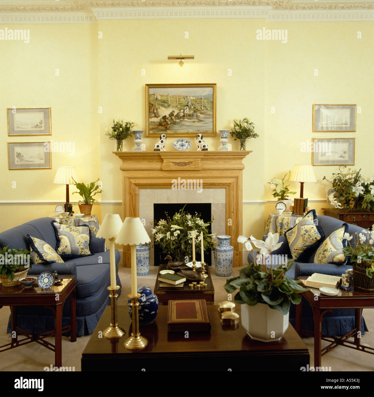 Pale yellow sittingroom with blue settees and picture above fireplace ...