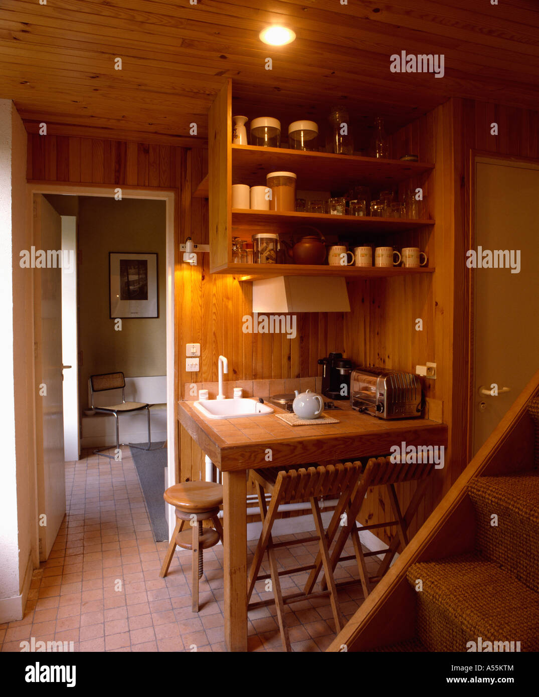 Compact kitchen in small hall with shelving and sink in wooden table ...