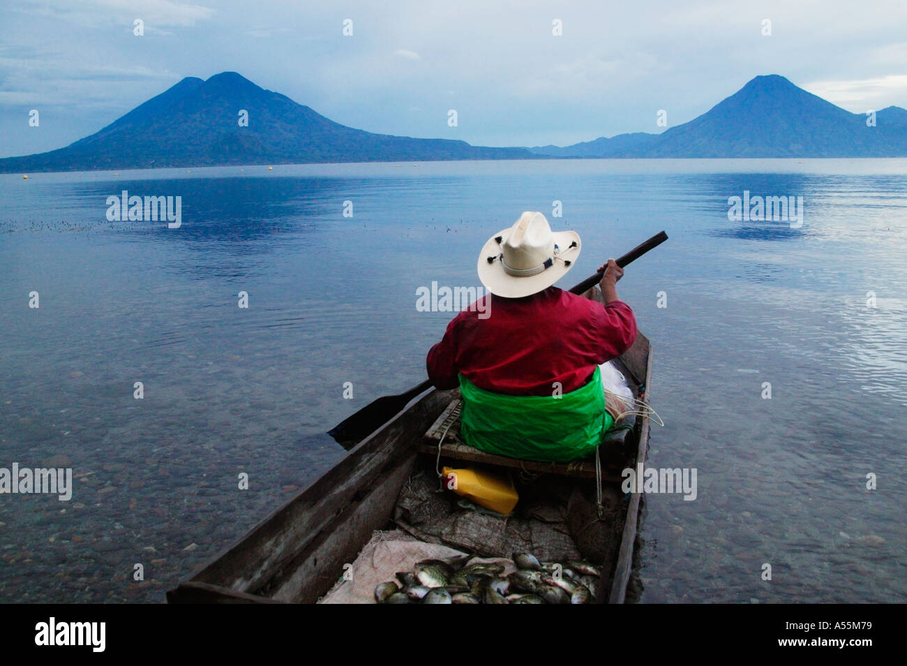 Man on canoe on Lake Atitlan volcanoes of Toliman and San Pedro Pana in ...