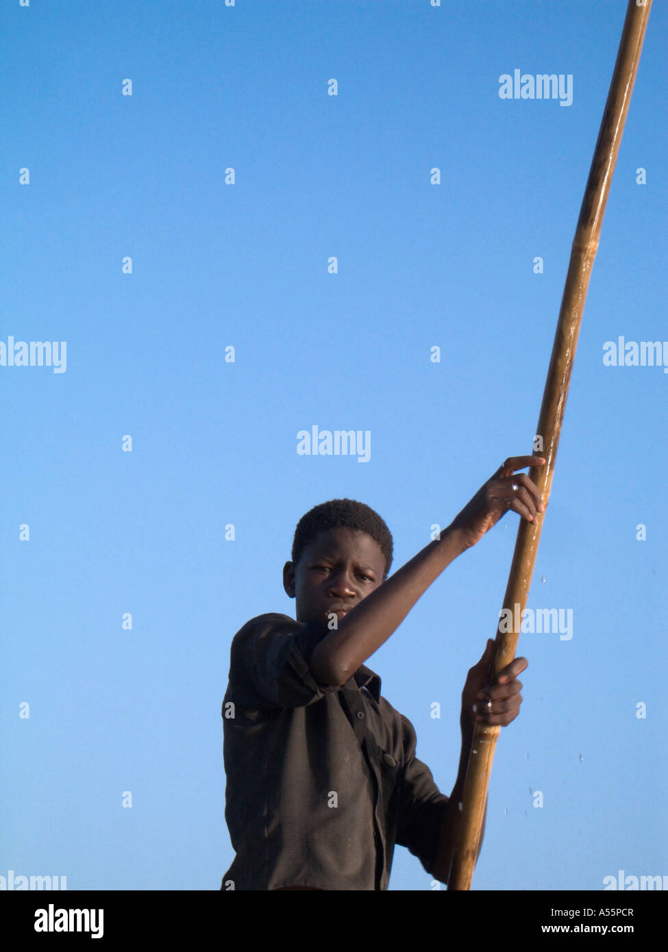 young boy using a pole to float across Niger River Stock Photo - Alamy