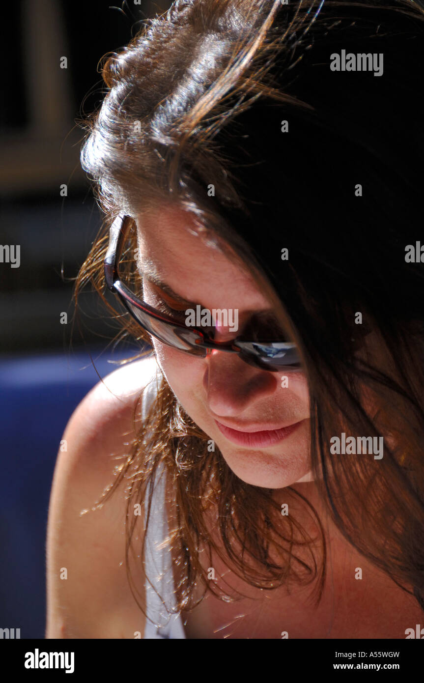 Woman sitting in sun with sunglasses concentrating on writing Stock ...